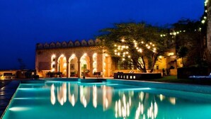 Área de piscina com um edifício ao fundo, cercada por árvores e luzes de Natal.