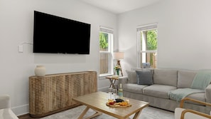 Uma sala de estar com televisão de tela plana, um armário de madeira, um sofá cinza e uma mesa de centro com uma travessa de frutas.
