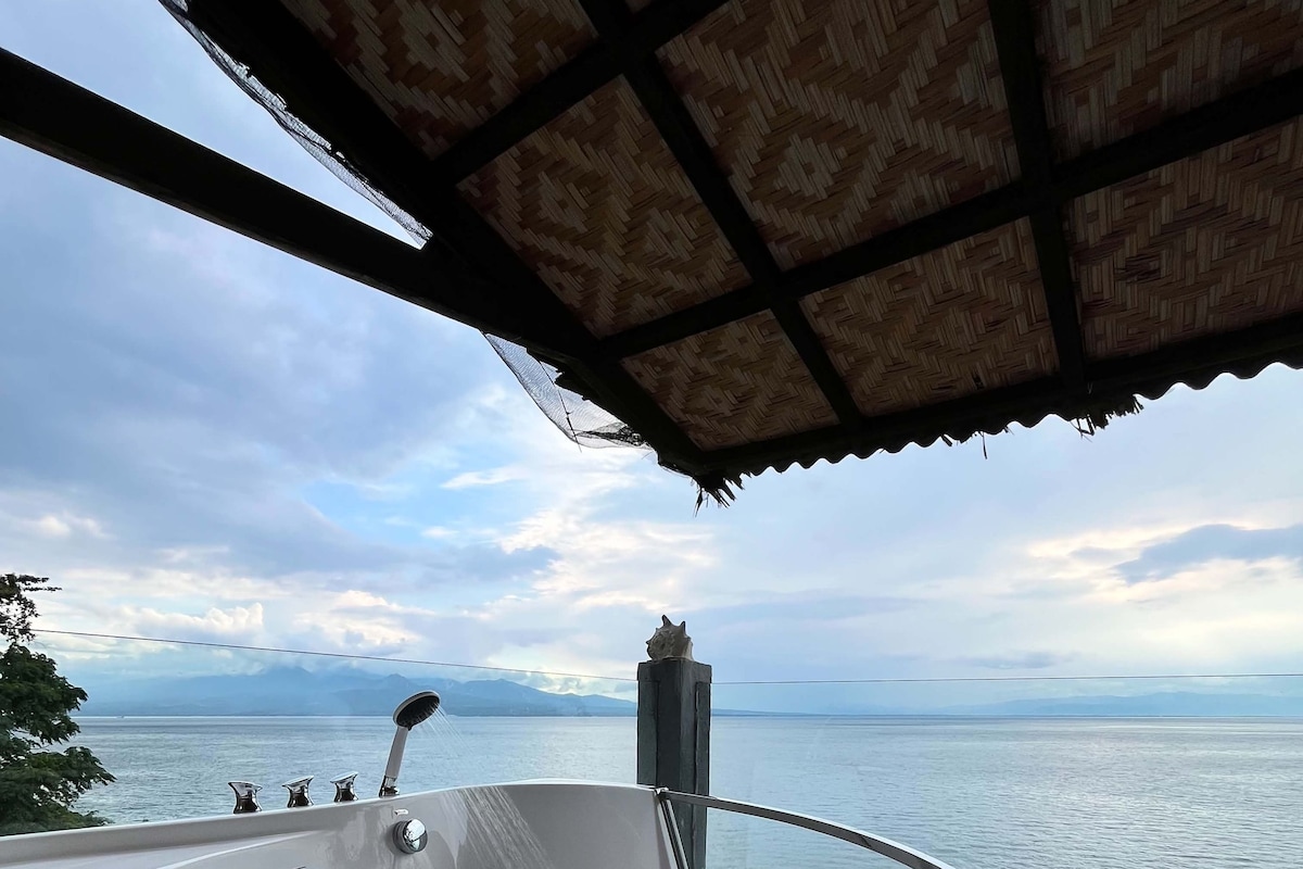 Banheira de hidromassagem decorada com flores e vista para o mar.