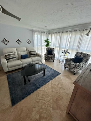 Sala de estar com sofá, poltrona, mesa de centro e um vaso de planta.