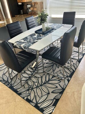 Uma área de refeições com mesa, cadeiras e um tapete decorativo.