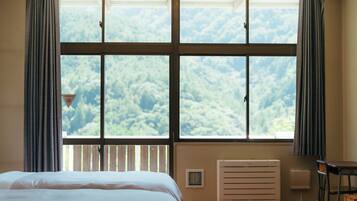 Quarto de hotel com uma janela grande, uma cama, uma escrivaninha e um ar condicionado.