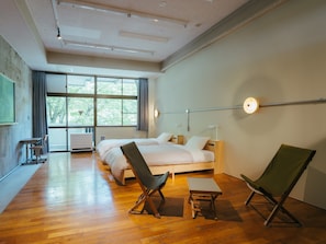 Quarto de hotel moderno com uma janela grande, cama, escrivaninha e uma cadeira.