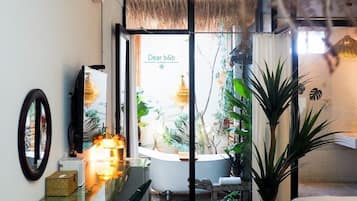 Casa de banho com banheira, espelho, lavatório e uma planta em vaso.