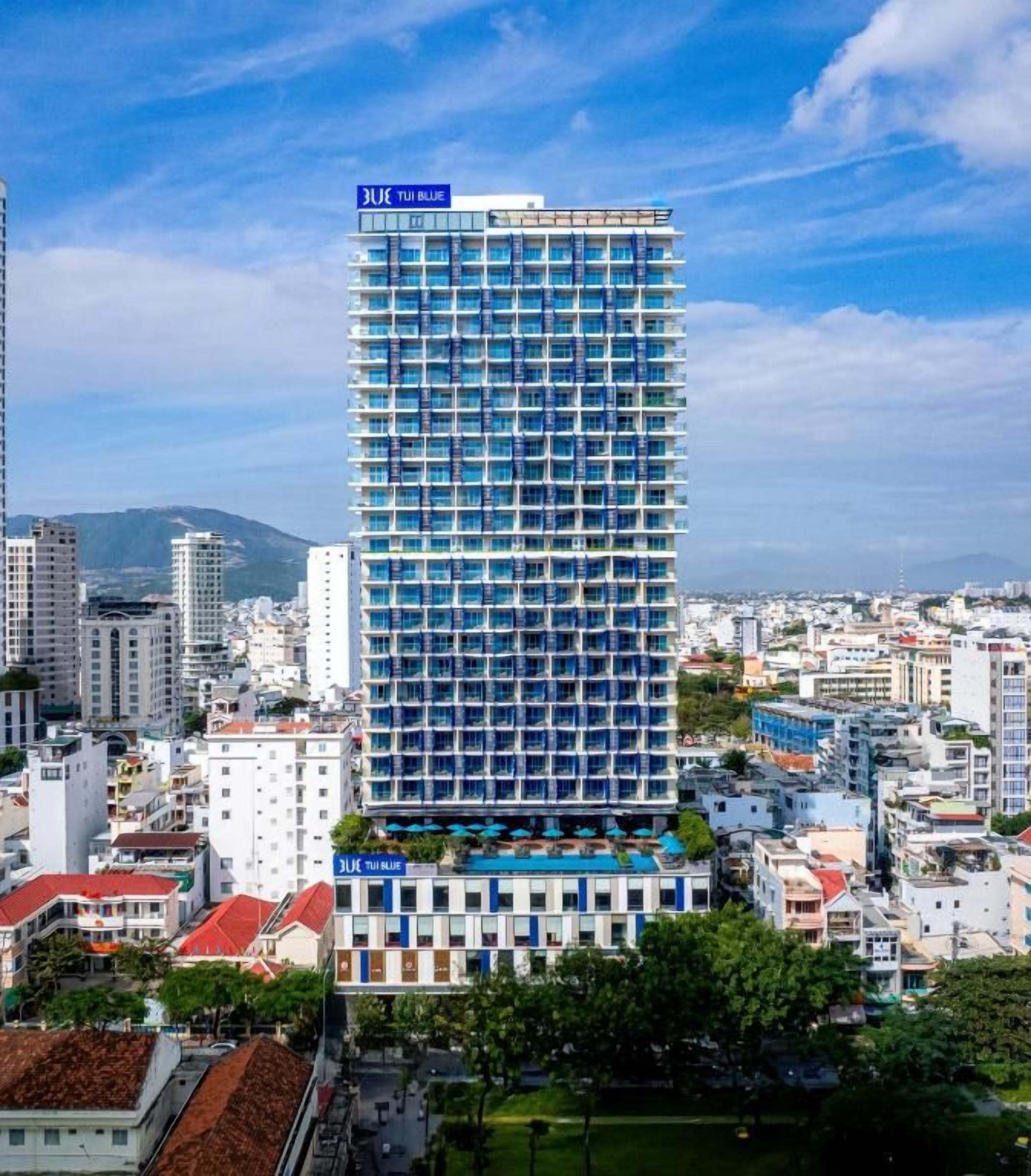 Hotel imponente com fachada de vidro moderna, várias varandas e uma sinalização chamativa no topo.