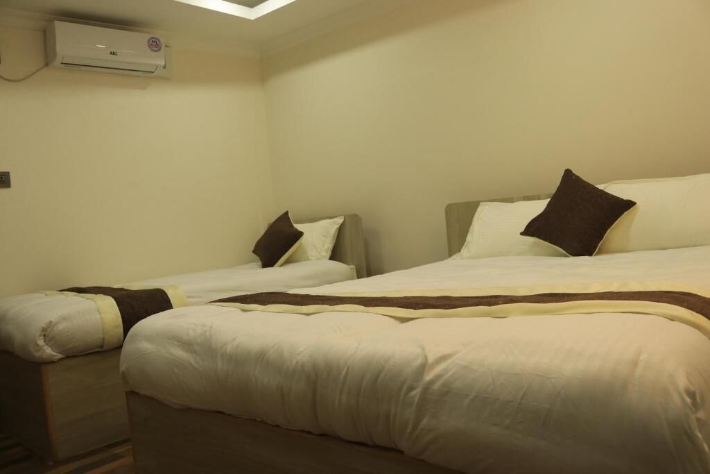 Quarto de hotel com duas camas, ar-condicionado no teto e luminária.