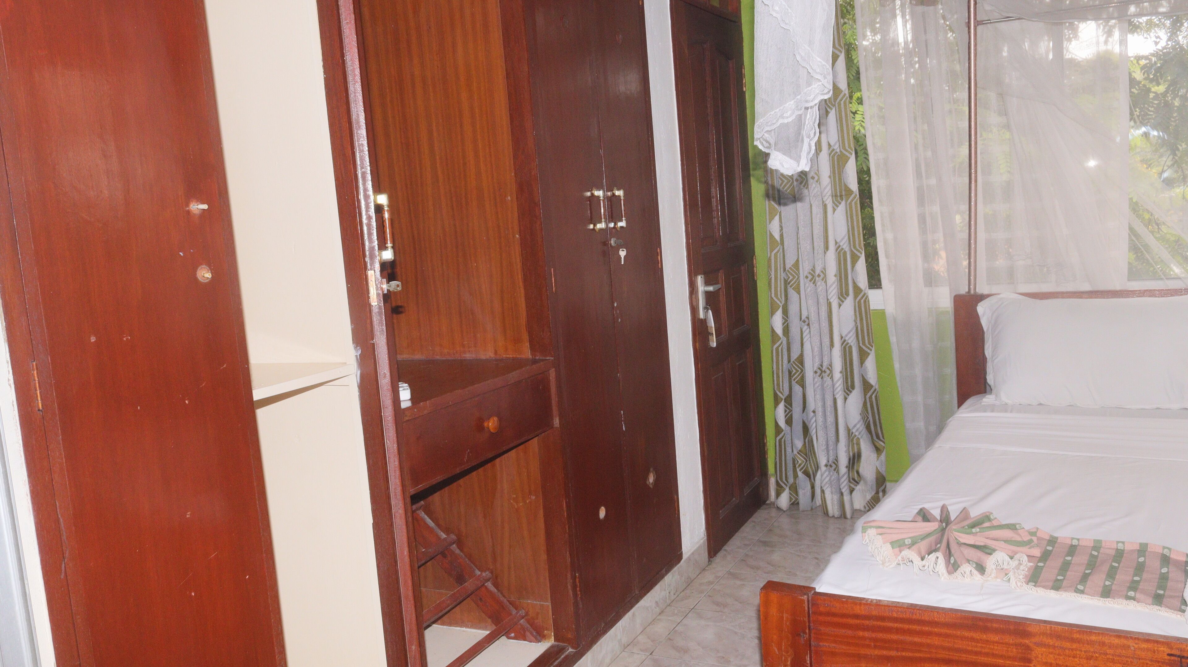 Quarto com cama, guarda-roupa de madeira e uma pequena escrivaninha.