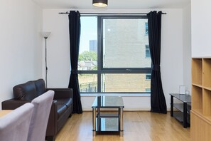 Uma sala de estar moderna com um sofá, uma mesinha e uma estante de livros.
