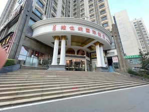 Entrada de um hotel com um arco imponente, degraus que levam a ele e vista clara dos edifícios altos ao redor.