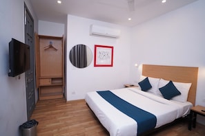 Quarto de hotel com cama, televisão, guarda-roupa e ar condicionado.