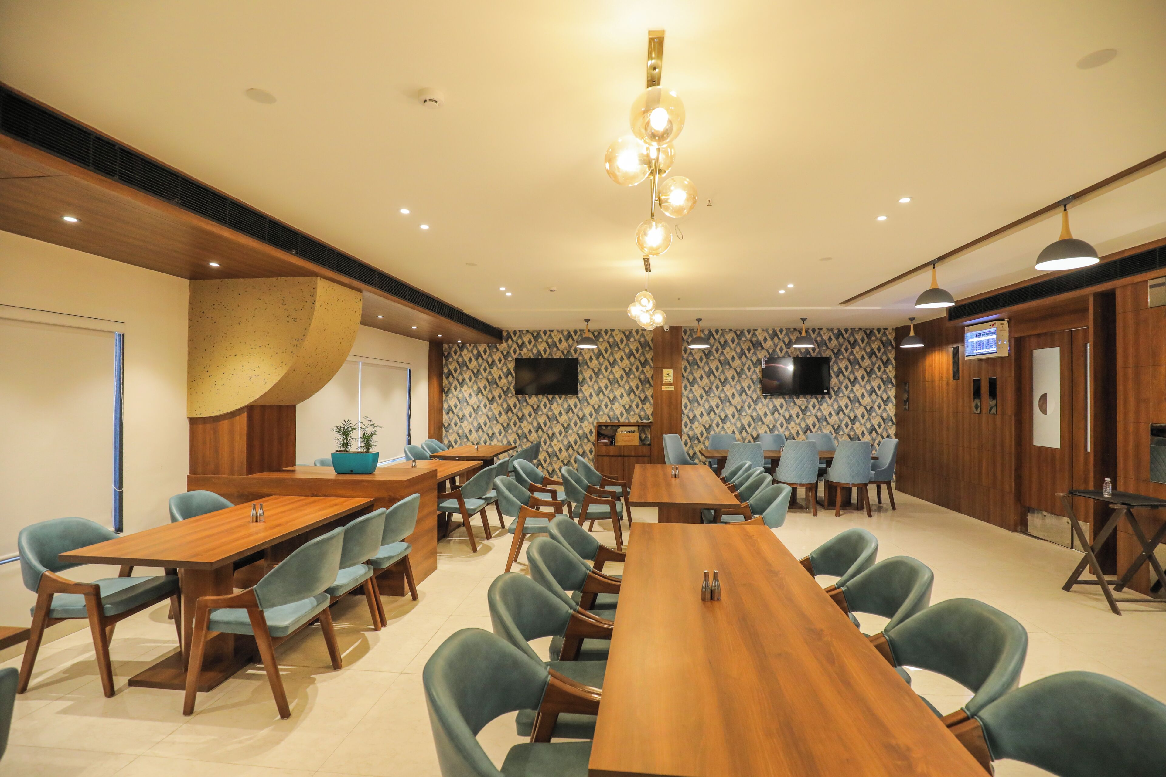 Sala de conferências com várias mesas e cadeiras, uma planta grande e um design moderno no teto.