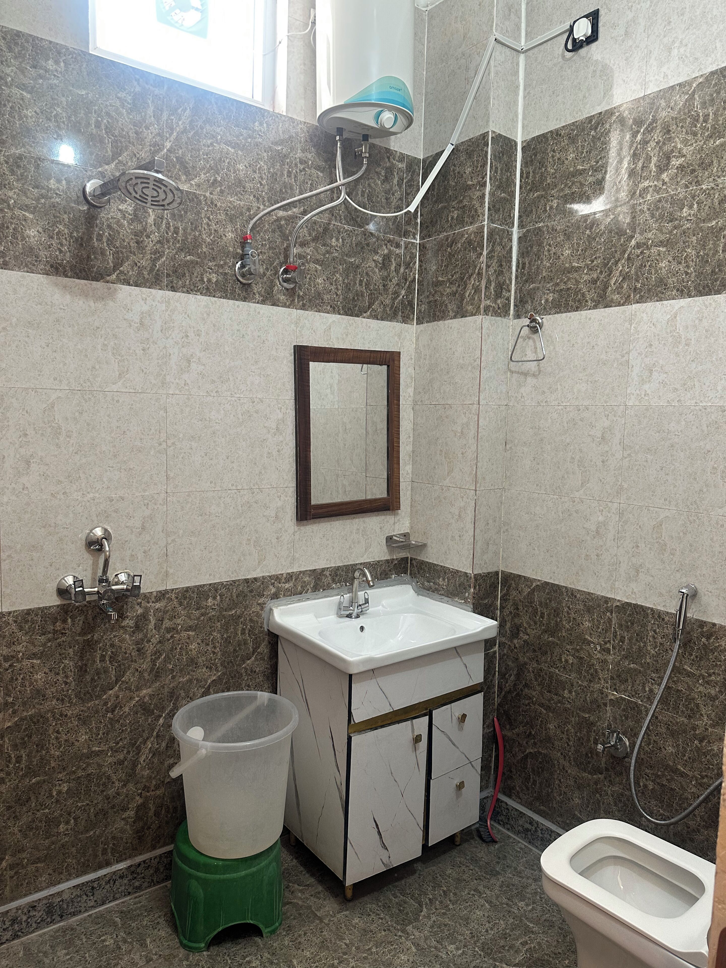Casa de banho com lavatório, espelho, chuveiro e sanita.