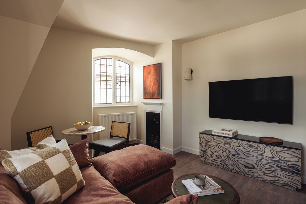 Uma sala de estar moderna com sofá, mesa de centro, lareira, televisão e janela com vista.