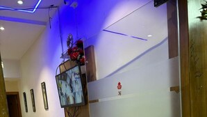 Entrada de hotel com porta de vidro fosco, uma câmera de segurança e uma placa com a inscrição 'HOTEL SAI VILLA'.