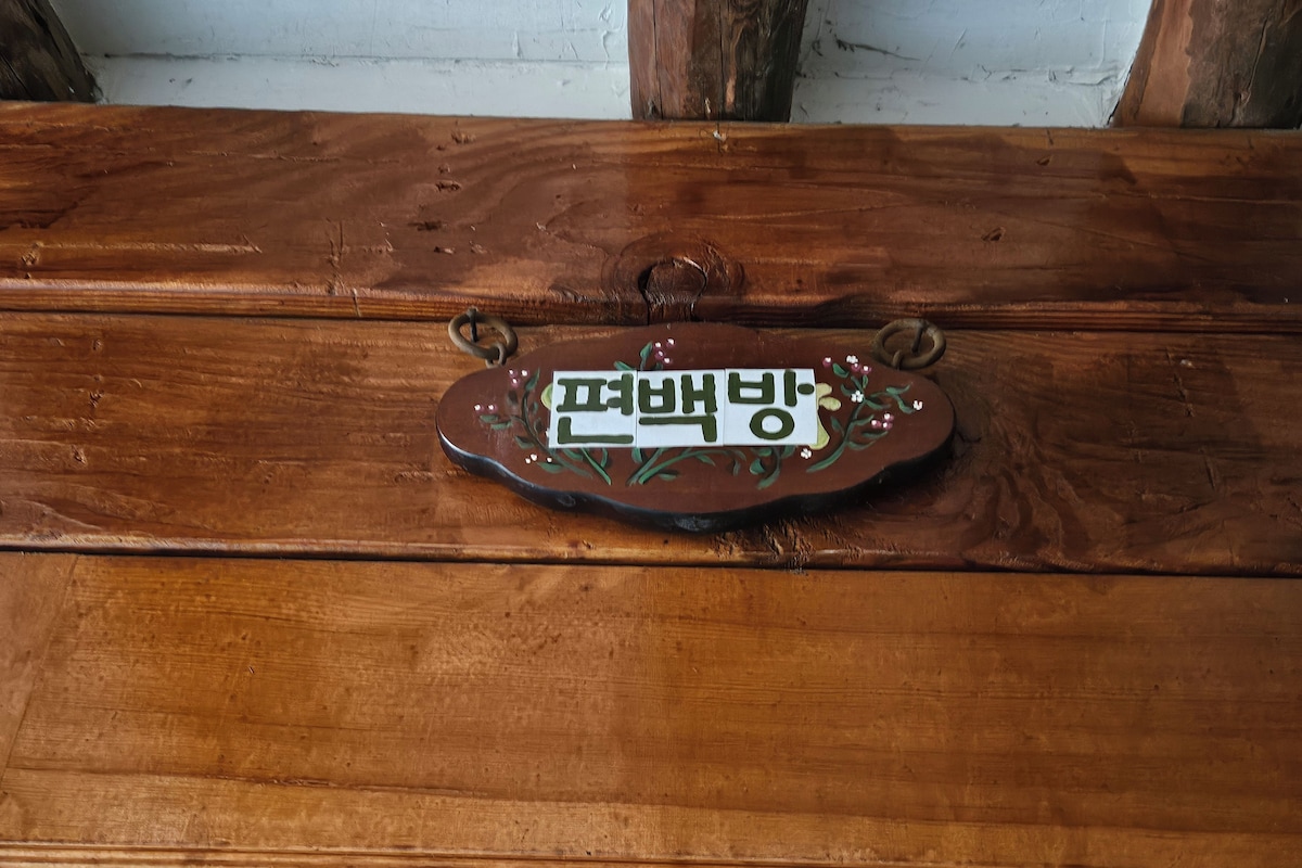 Baú de madeira com fecho de metal e placa decorativa com caracteres coreanos.