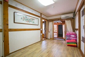 Um corredor com piso de madeira, um quadro na parede e uma pilha de toalhas coloridas.