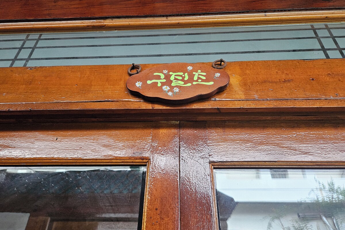 Uma porta de madeira com uma placa de metal e uma janela com reflexo.