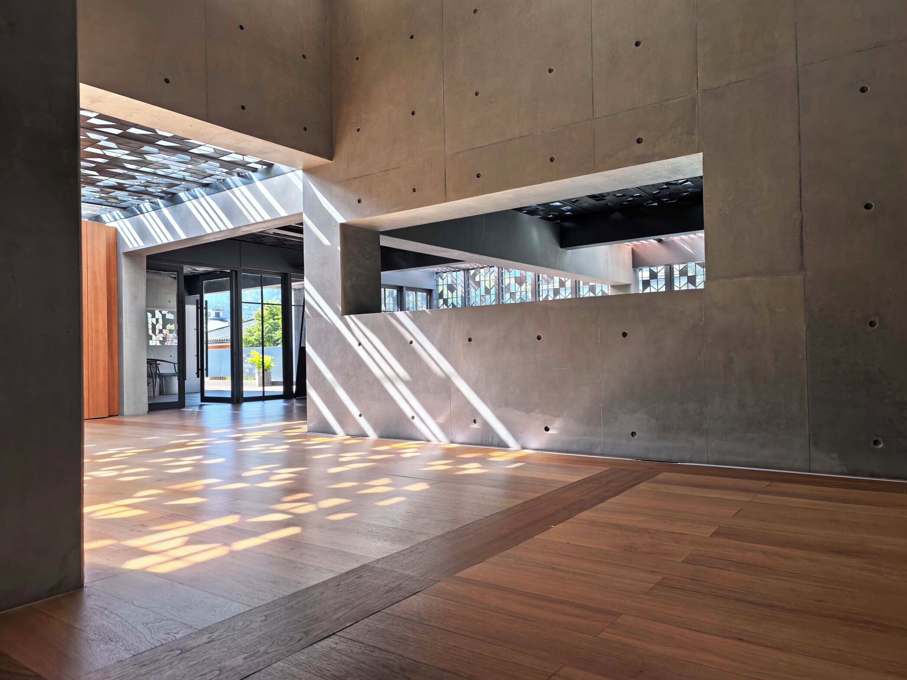 Um interior moderno com piso de madeira, paredes de concreto e uma escada.
