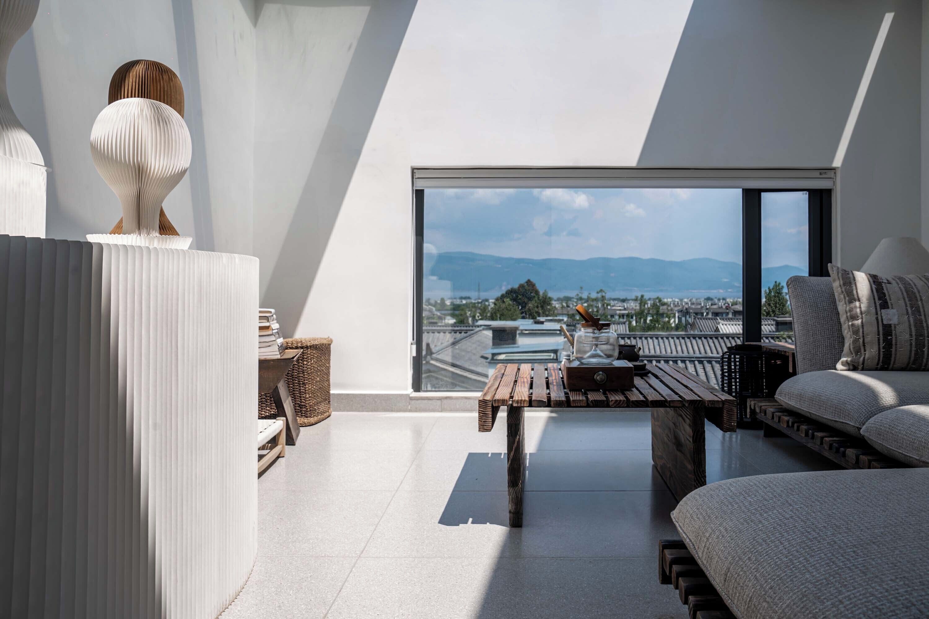 Uma sala de estar moderna com uma janela ampla, uma mesa de madeira e um sofá.