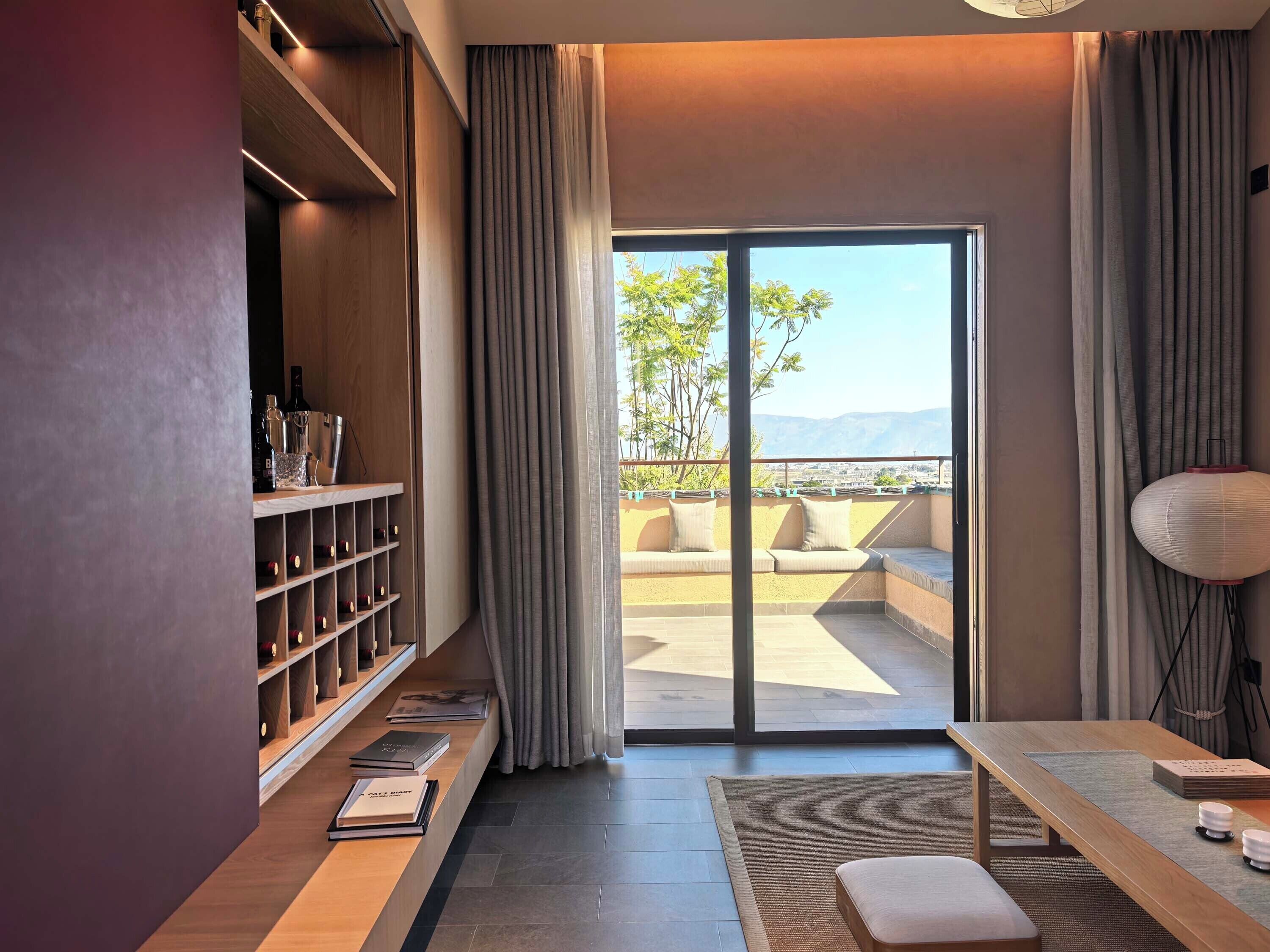 Quarto moderno com espaço para vinhos embutido, área de estar com vista e porta de vidro deslizante grande.