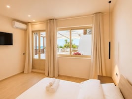 Quarto de hotel com cama, cortinas, televisão e janela vista para o exterior.