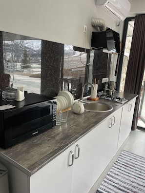 Cozinha moderna com micro-ondas embutido, pia e uma janela ampla com vista para uma paisagem nevada.