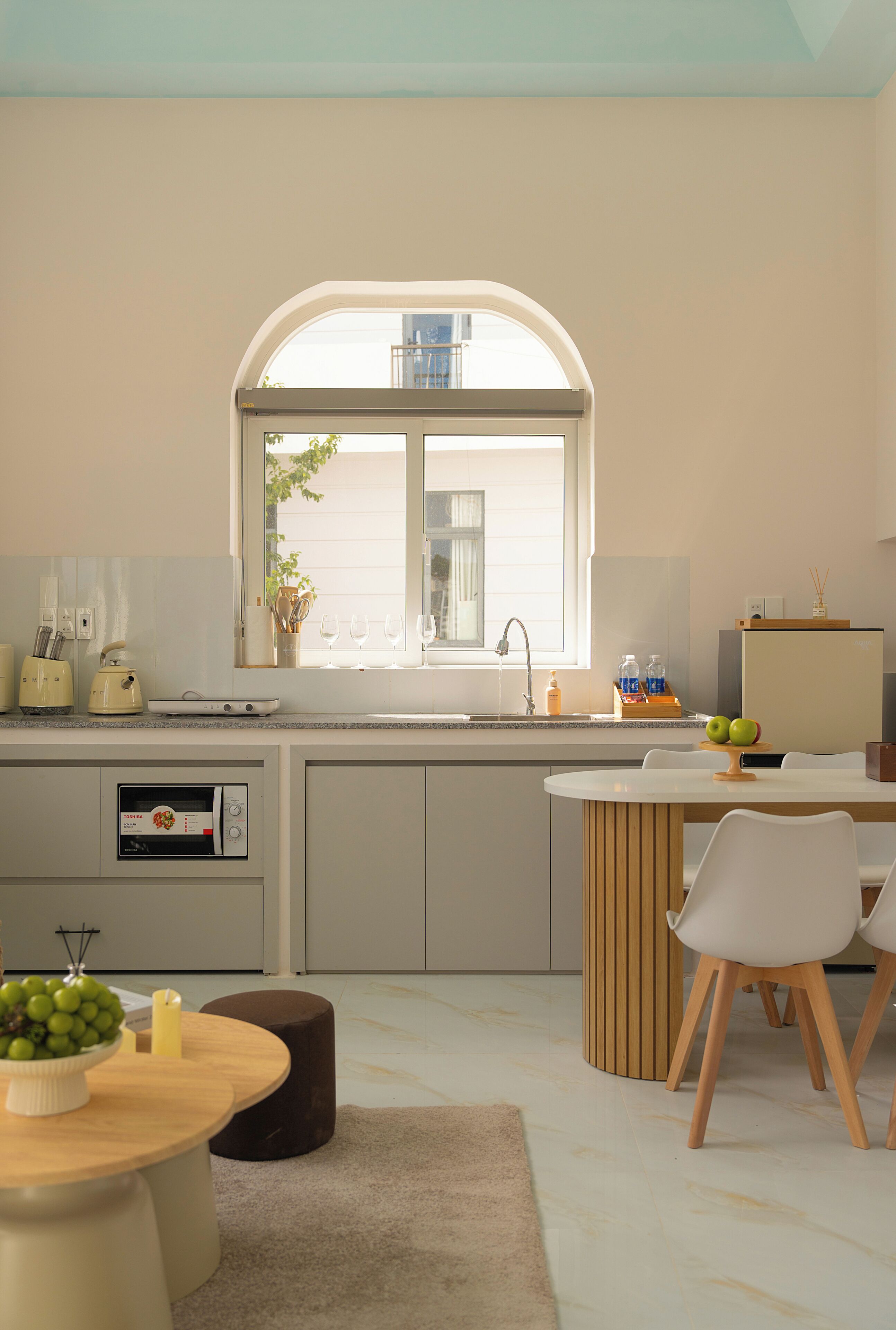 Cozinha moderna com uma janela ampla, área de refeições com mesa redonda e máquina de lavar integrada.