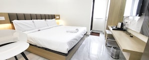 Quarto de hotel com cama, mesa de cabeceira, cadeira e vista para o exterior.