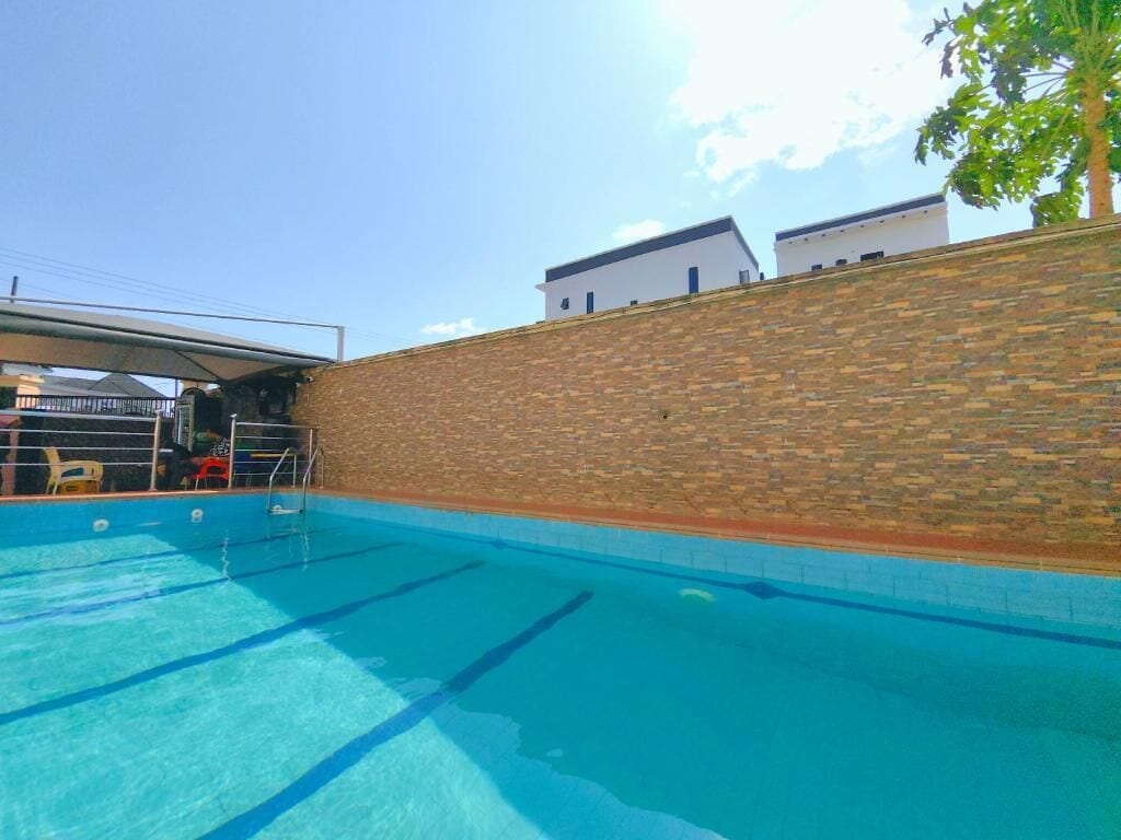 Piscina com muro de tijolos e área coberta.