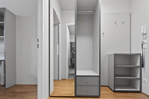 Quarto moderno e minimalista com roupeiro embutido, uma pequena escrivaninha e estantes.