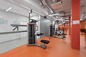 Academia com equipamentos de ginástica, um banco e uma parede com um logotipo grande.