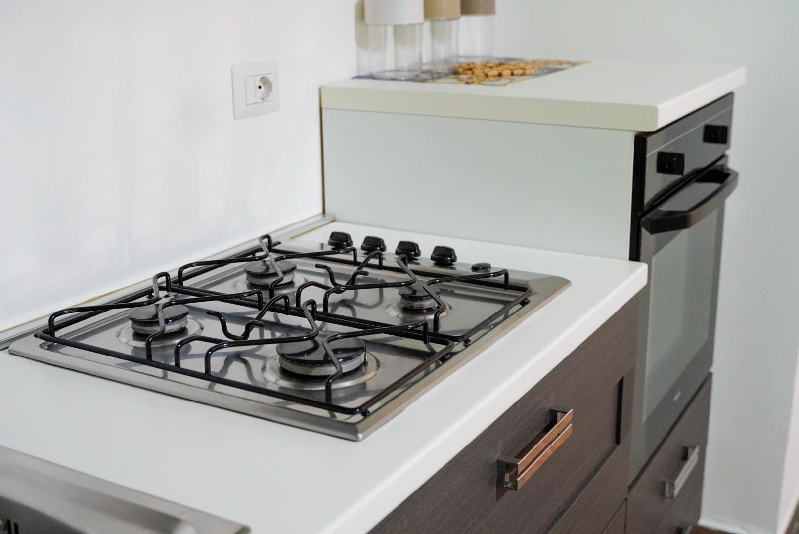 Cozinha com fogão a gás, forno e bancada branca.