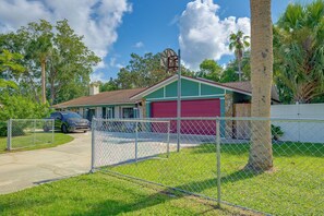 Um imóvel residencial com entrada cercada, garagem e uma casa com porta de garagem vermelha.