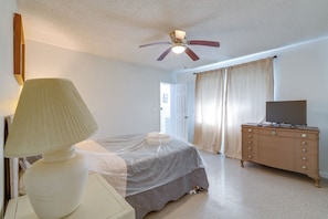 Quarto com cama, penteadeira, ventilador de teto e luminária.