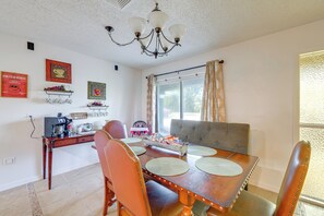 Uma sala de jantar com uma mesa de madeira, cadeiras, um lustre e obras de arte nas paredes.
