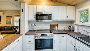 Uma cozinha moderna com armários brancos, forno Bosch, micro-ondas e fogão a gás.