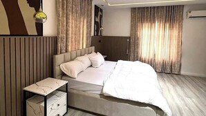 Quarto moderno com cama, mesas de cabeceira e uma parede com arte em silhueta.