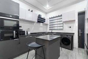 Cozinha moderna com ilha central, eletrodomésticos embutidos e máquina de lavar roupa.
