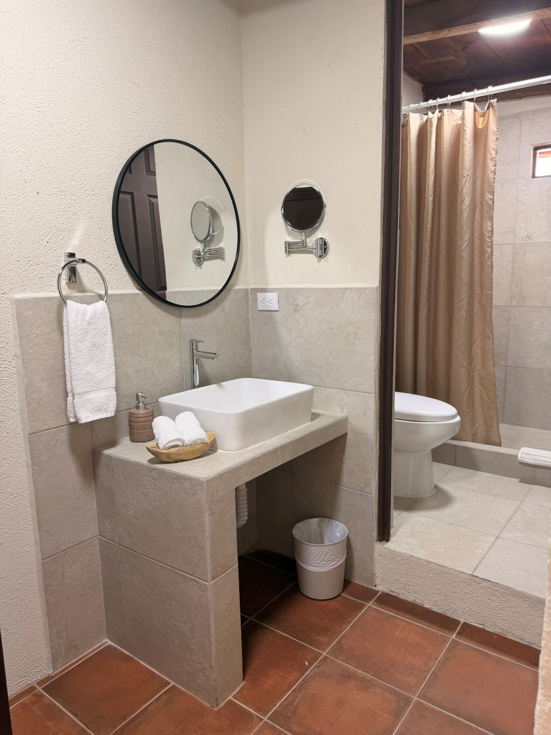 Casa de banho com pia, espelho, porta-toalhas e cortina de chuveiro.