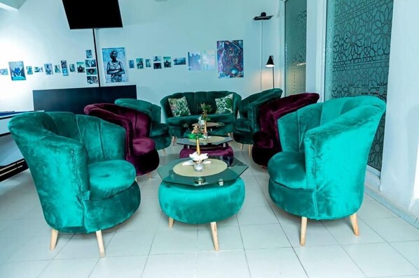 Sala de estar com sofá verde, mesa de centro e televisão de tela plana.