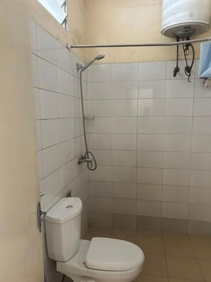 Um banheiro pequeno, com azulejos, incluindo vaso sanitário, chuveiro e porta-toalhas.