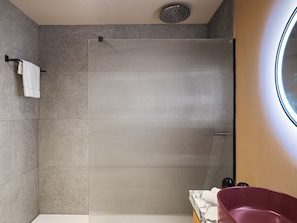 Casa de banho moderna com chuveiro, bancada de mármore e banheira vermelha.