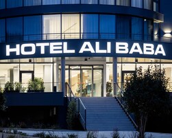 Entrada moderna de hotel com escadaria que leva às portas, cercada por vegetação.