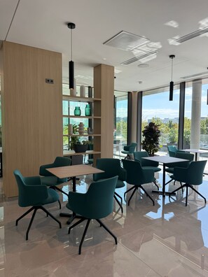 Decoração moderna com mesa e cadeiras de vidro, um pilar de madeira e vista através de grandes janelas.