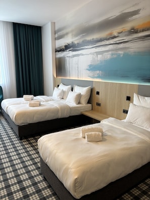 Quarto de hotel com duas camas, um quadro abstrato grande na parede e um chão xadrez.
