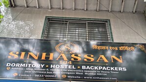 Placa de hostel com o nome 'SINHASSAN' e informações de contato.