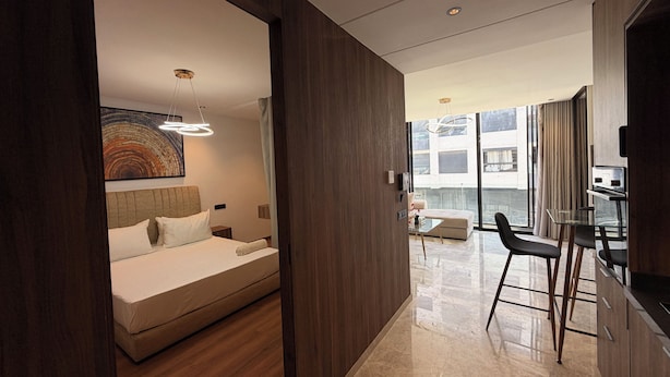 Quarto de hotel moderno com uma cama grande, uma escrivaninha e vista para a cidade.
