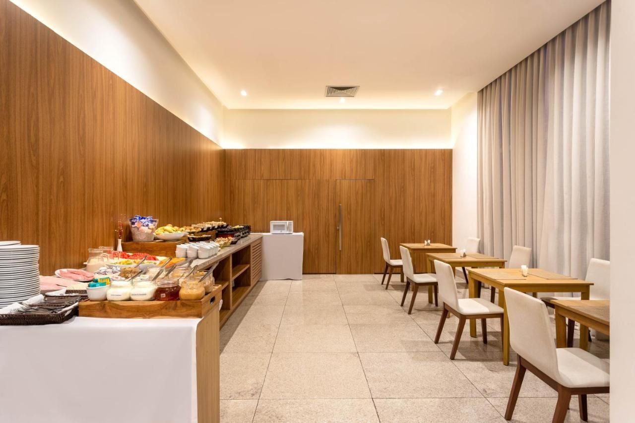 Espaço de café da manhã com buffet, assentos e micro-ondas.