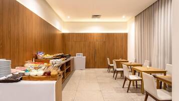 Espaço de café da manhã com buffet, assentos e micro-ondas.