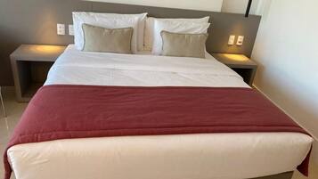 Quarto de hotel moderno com uma cama grande, duas mesas de cabeceira e uma cabeceira.
